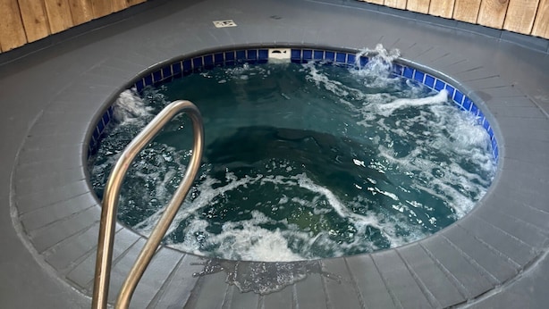 Uma banheira de hidromassagem com escada de metal e uma piscina com escada.