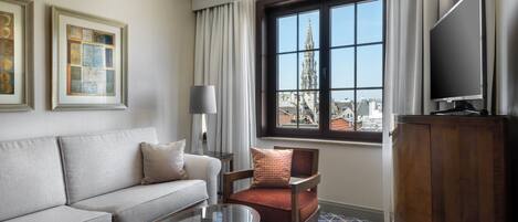 Quarto de hotel moderno com sofá, poltrona e televisão.