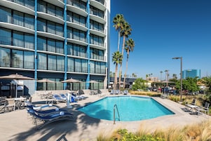Um hotel com piscina, espreguiçadeiras e palmeiras.