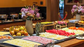 Um buffet com diversas frutas e um vaso de flores.