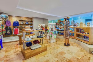 Uma loja de varejo com prateleiras de roupas, acessórios e uma vitrine de chapéus.