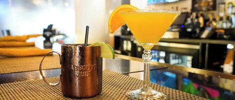 Uma área de bar com um copo de cobre e uma taça de martini sobre um tapete tecido.