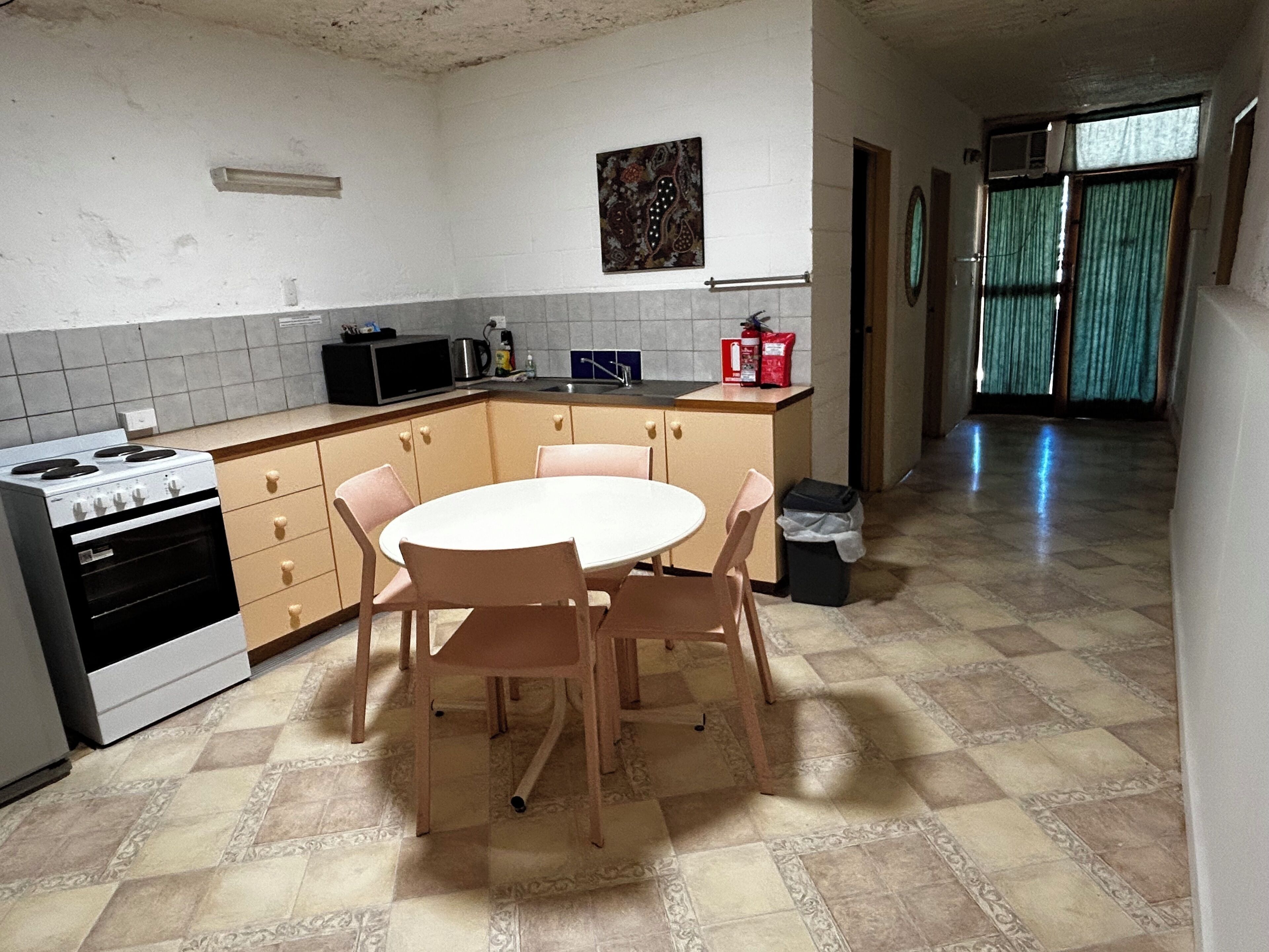 Cozinha compacta com fogão, micro-ondas e pia. Há uma mesa de jantar com quatro cadeiras.