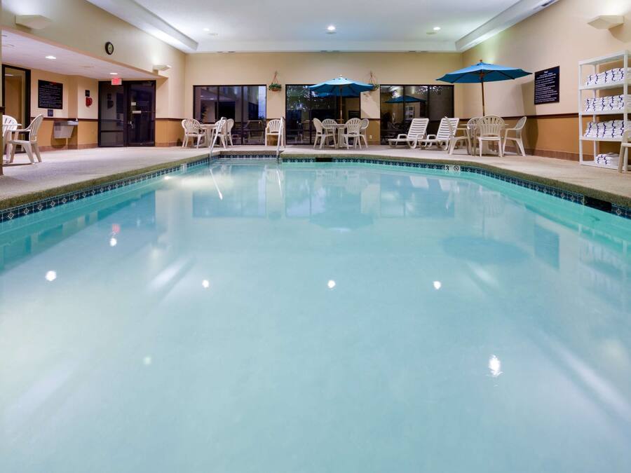 Uma piscina coberta grande com espreguiçadeiras e guarda-sóis.