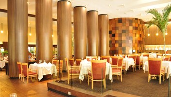 Restaurante com várias mesas e cadeiras, colunas cilíndricas grandes e um design de parede xadrez.