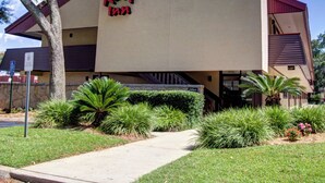 Um Red Roof Inn com telhado vermelho, paredes bege e entrada pavimentada.