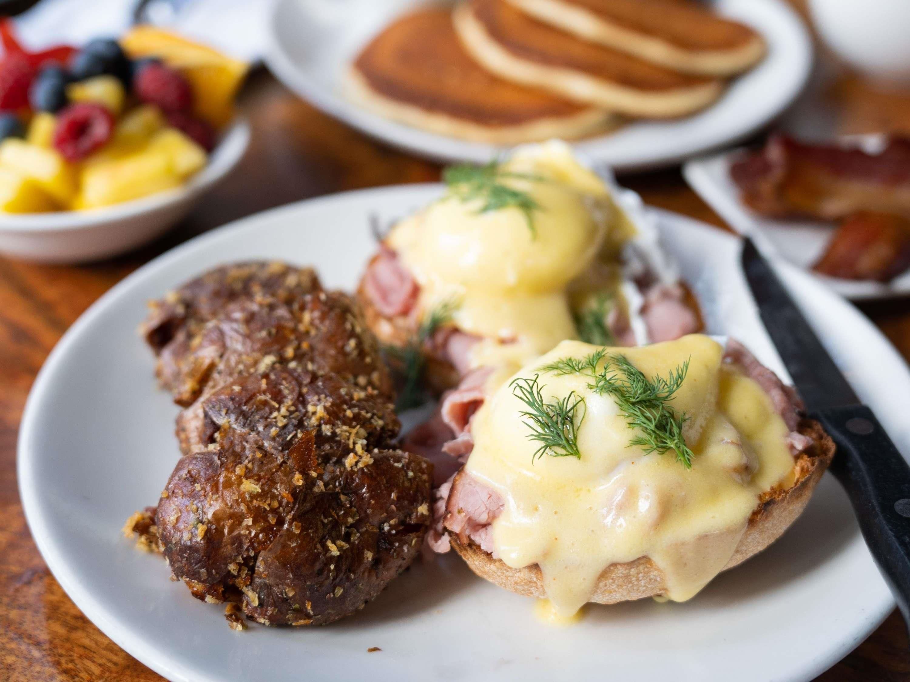 Prato de pequeno-almoço com ovos Benedict e batata palha.