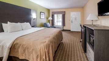 Quarto de hotel com uma cama grande, uma escrivaninha com cadeira, televisão e guarda-roupa.