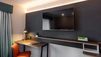 Quarto de hotel com escrivaninha, cadeira e um espelho grande.