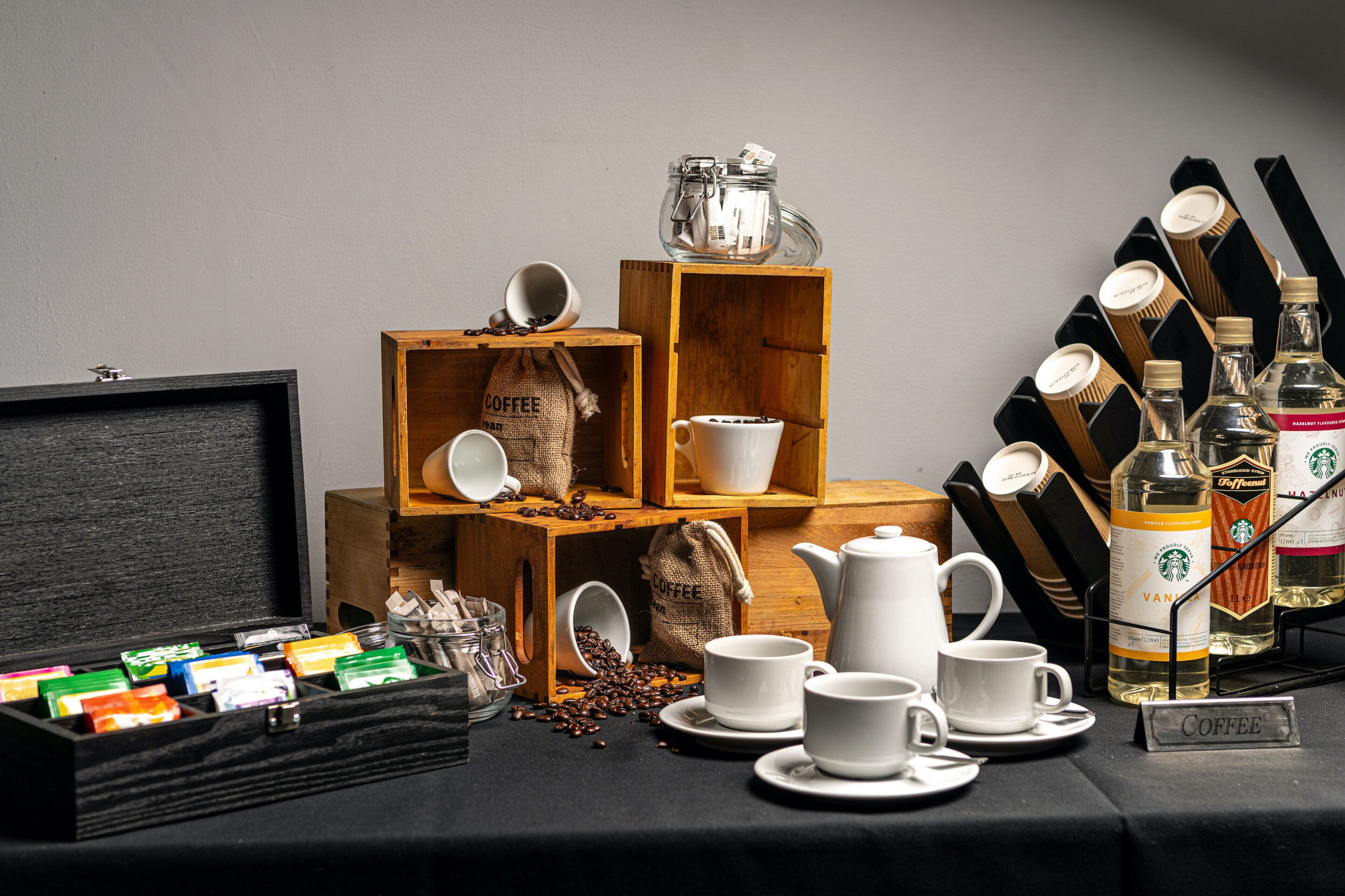 Um espaço com estação de café, diversos equipamentos para preparo, grãos de café e garrafas da Starbucks.