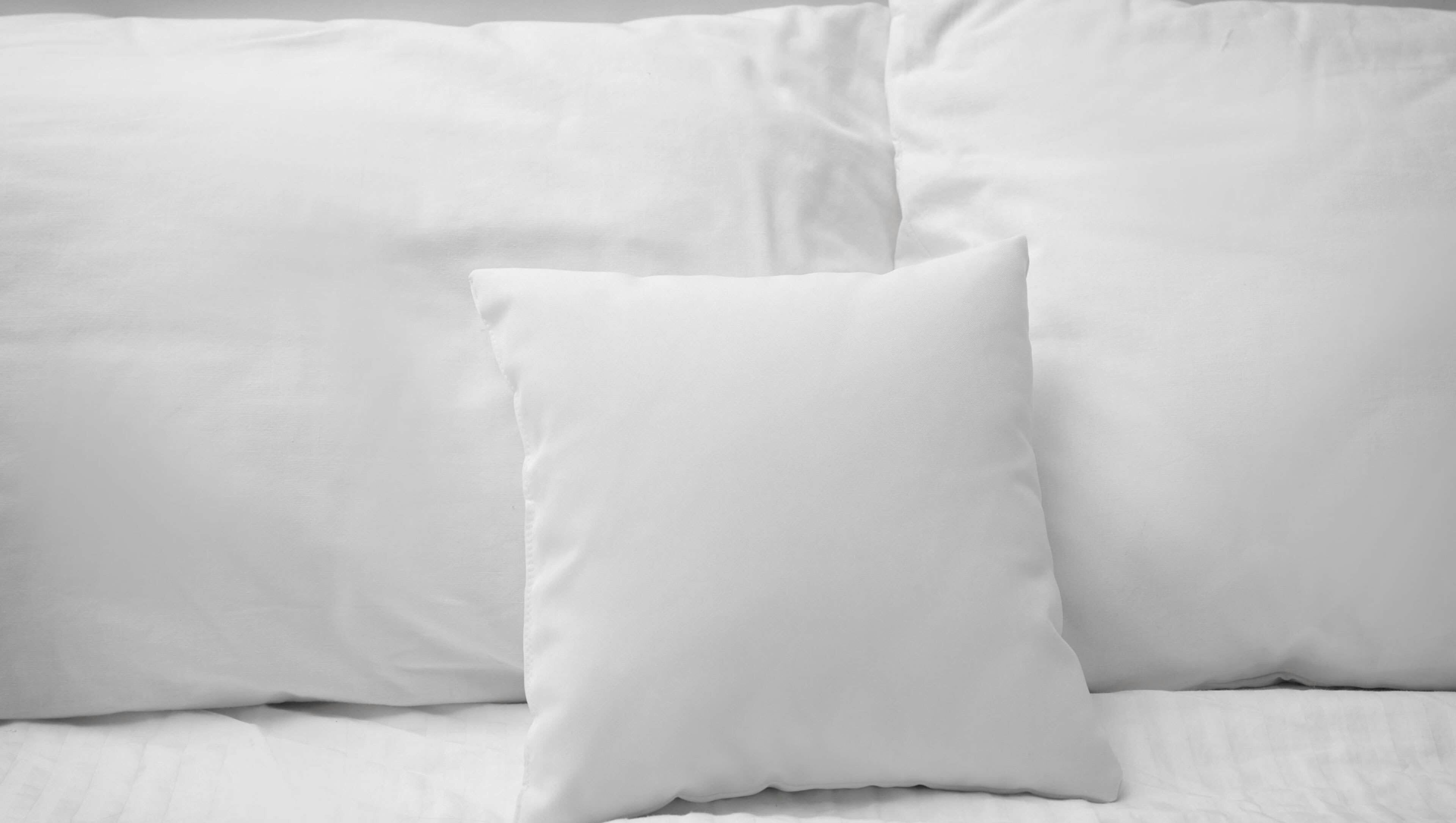 Uma cama com roupa de cama e travesseiros brancos.