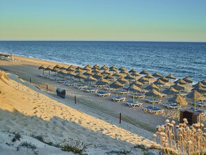 Na praia, espreguiçadeiras, guarda-sóis, toalhas de praia 