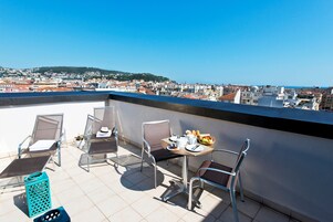 Terraço no telhado com uma mesa posta para dois, duas cadeiras e vista para a paisagem urbana.