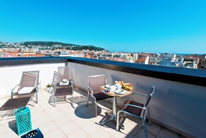 Terraço com mesa posta para café da manhã, com vista para a cidade.