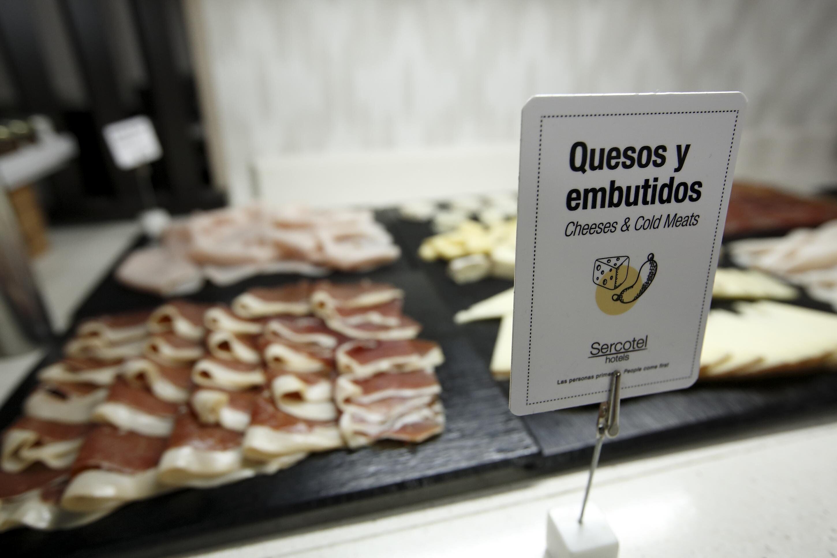 Exposição de queijos e charcutaria em um buffet de hotel.