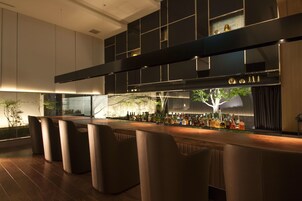 Uma área de bar moderna com um balcão comprido, vários bancos e uma variedade de garrafas.