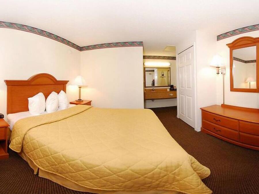 Quarto de hotel com cama, abajures, penteadeira, televisão e espelho.
