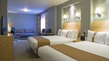 Quarto de hotel com duas camas, um sofá, uma escrivaninha e uma televisão.