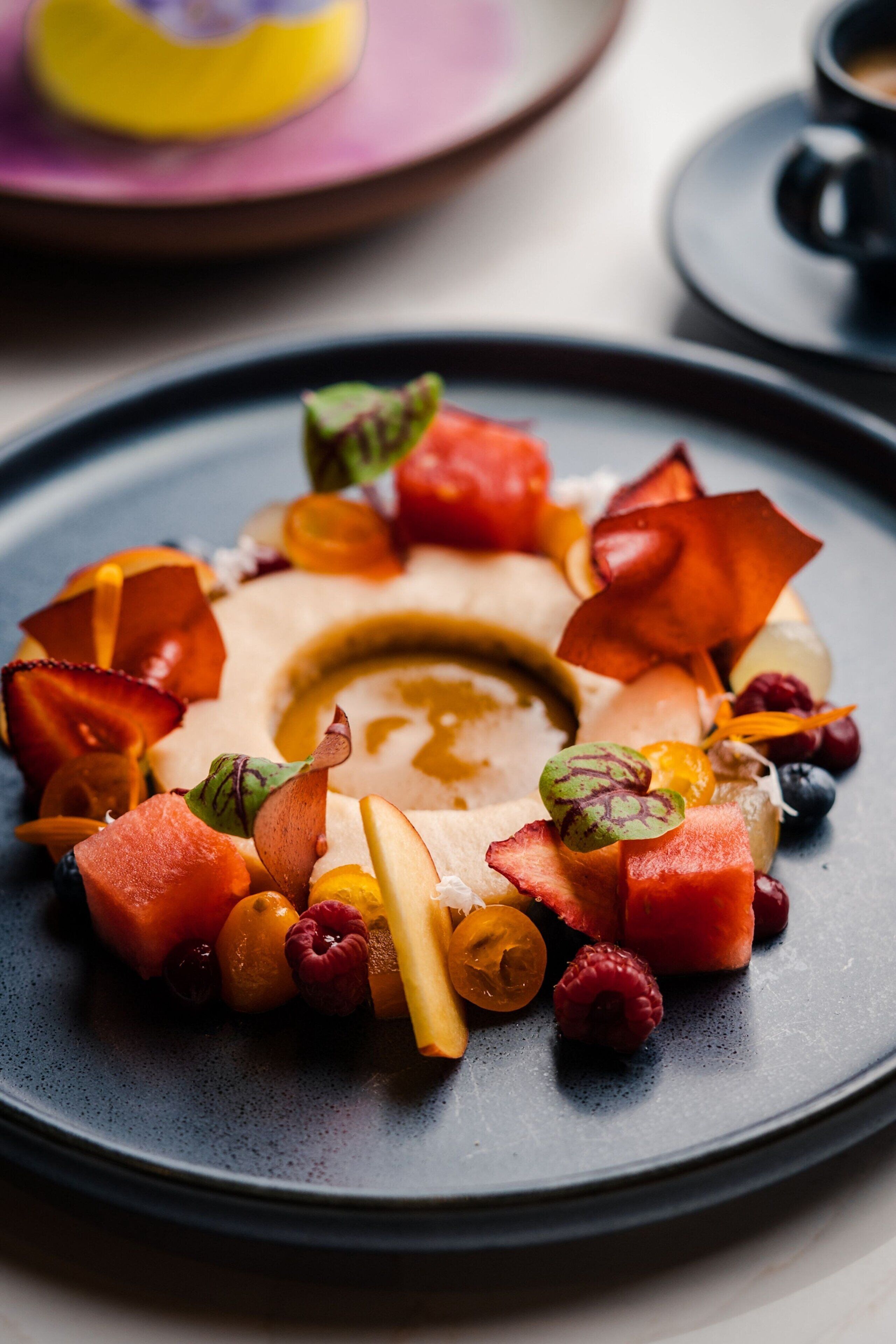 Um prato de sobremesa com diversas frutas e um fio de caramelo.