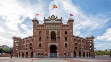 Um edifício grande e histórico com um arco central, várias varandas e uma bandeira no topo.