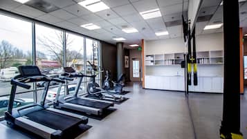 Uma academia com esteiras, bicicletas ergométricas e máquina de musculação.