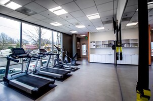 Uma academia com esteiras, bicicletas ergométricas e máquina de musculação.