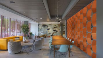 Uma sala de conferências moderna com uma longa mesa de madeira, cadeiras azuis e um sofá amarelo.