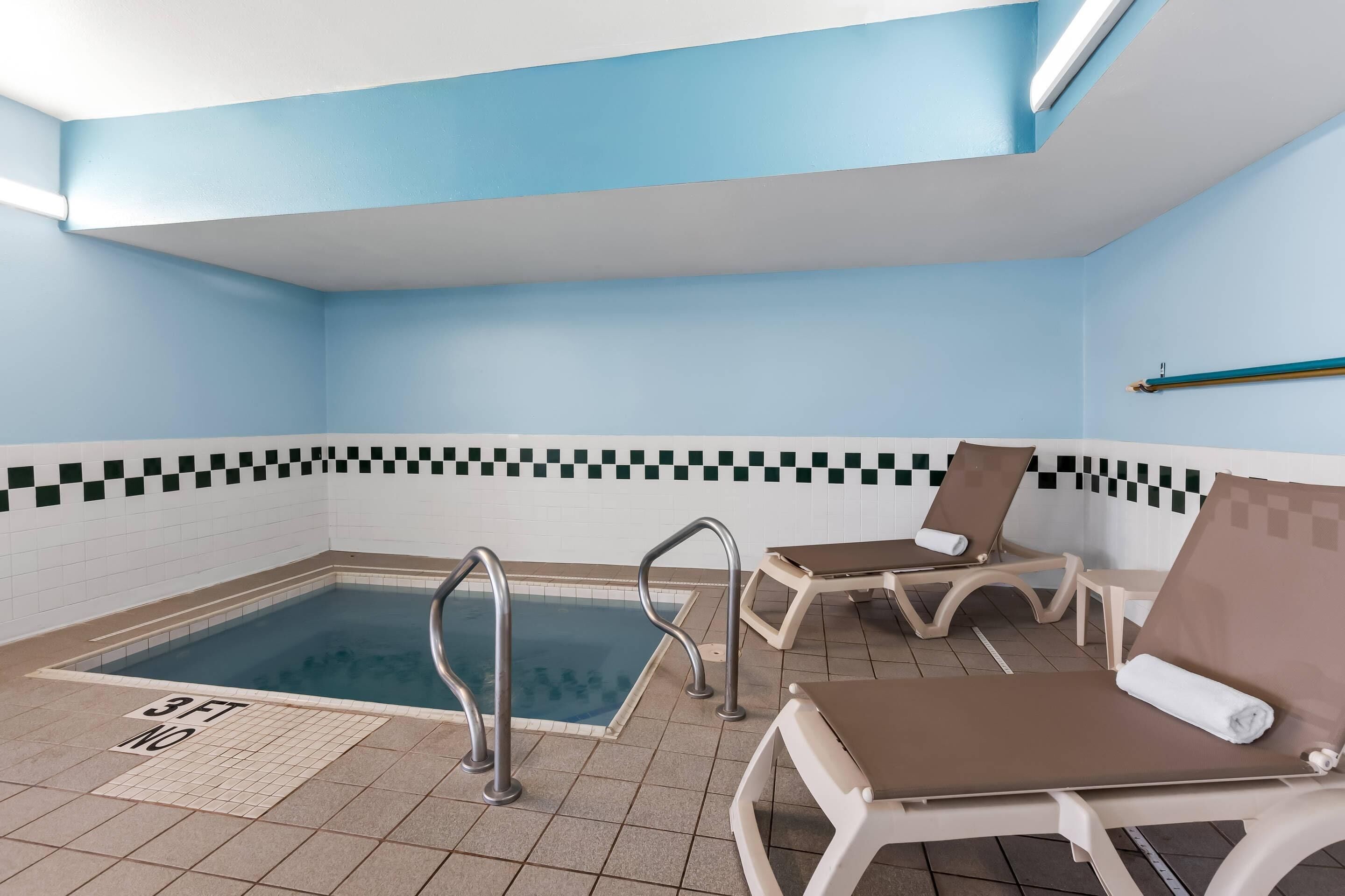Área da piscina com placa indicando 'não entrar com 3 pés de profundidade', cadeiras de descanso e piso em azulejo.