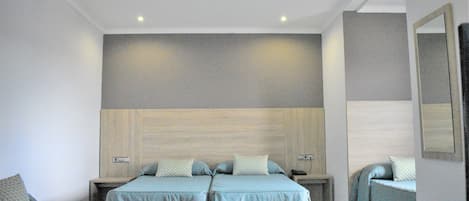 Quarto de hotel com duas camas, uma cabeceira de madeira e um espelho grande na parede.