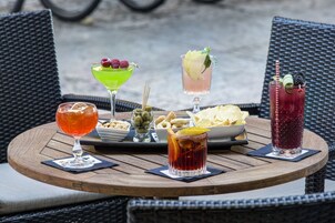 Mesa de madeira redonda com quatro bebidas e um suporte para petiscos.