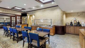 Restaurante com buffet, cadeiras azuis e piso de azulejos.