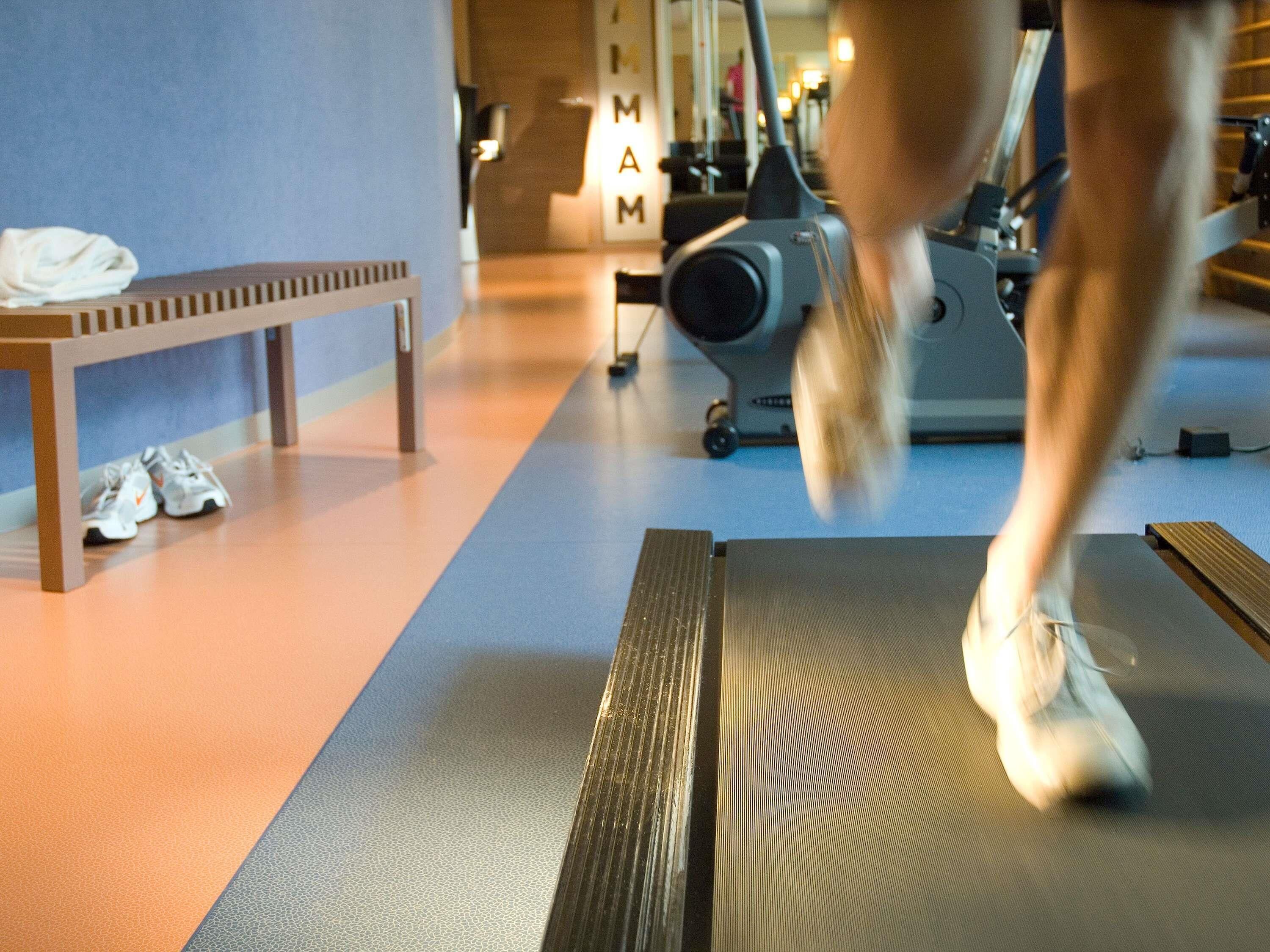 Uma academia com equipamentos de exercício, um banco e um par de tênis.