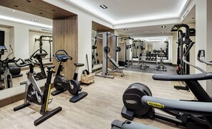 Uma academia com equipamentos de cardio, pesos e espelhos.