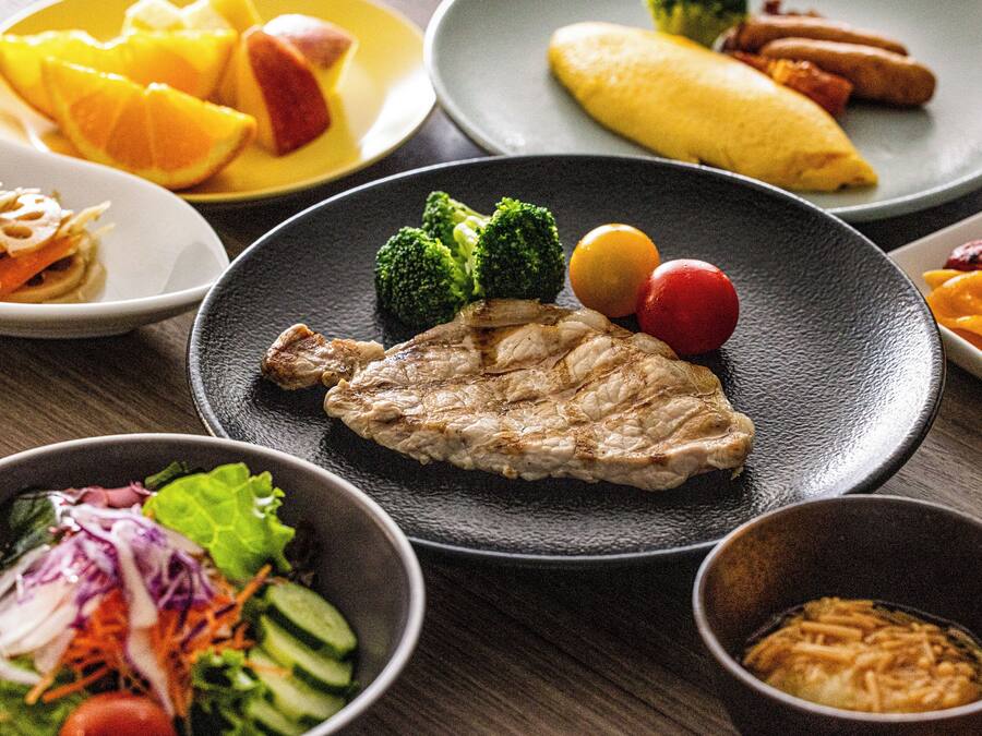 Diversos pratos com carne grelhada, legumes e frutas em uma mesa de jantar.