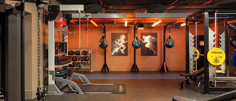Academia com equipamentos de musculação, um banco e um saco de pancada.