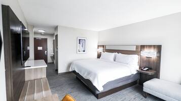 Quarto de hotel moderno com uma cama grande, uma mesa, uma cadeira e uma televisão.