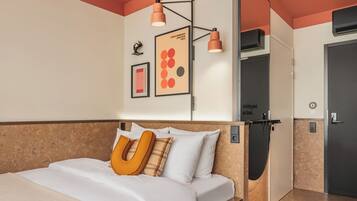 Quarto de hotel moderno com cama, obras de arte e uma porta.