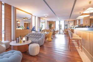 Um interior moderno com área de bar, assentos e balcão de recepção.