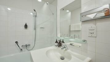 Casa de banho moderna com cabine de duche em vidro, lavatório branco e espelho com prateleira de vidro acima.