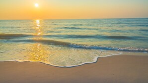 Uma praia com ondas suaves e um pôr do sol.