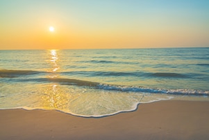 Uma praia com ondas suaves e um pôr do sol.