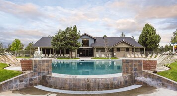 Uma casa moderna com piscina, varanda coberta e gramado bem cuidado.