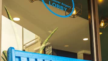 Um banco azul em frente a um edifício com uma placa que diz 'Accent Inn Vancouver Airport Lobby'.