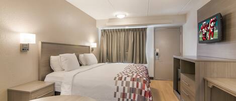 Quarto de hotel com cama, mesas de cabeceira, televisão, escrivaninha e guarda-roupa.