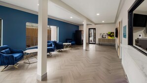 Ampla sala de estar com parede azul de destaque, piso de madeira e móveis modernos, incluindo sofás azuis e uma mesa de centro.