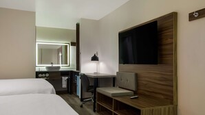 Quarto de hotel com duas camas, uma escrivaninha com abajur, televisão e espelho.
