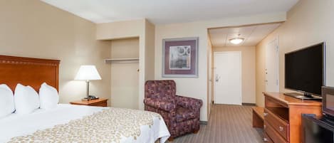 Quarto de hotel com uma cama grande, uma cadeira, uma televisão e uma cômoda.