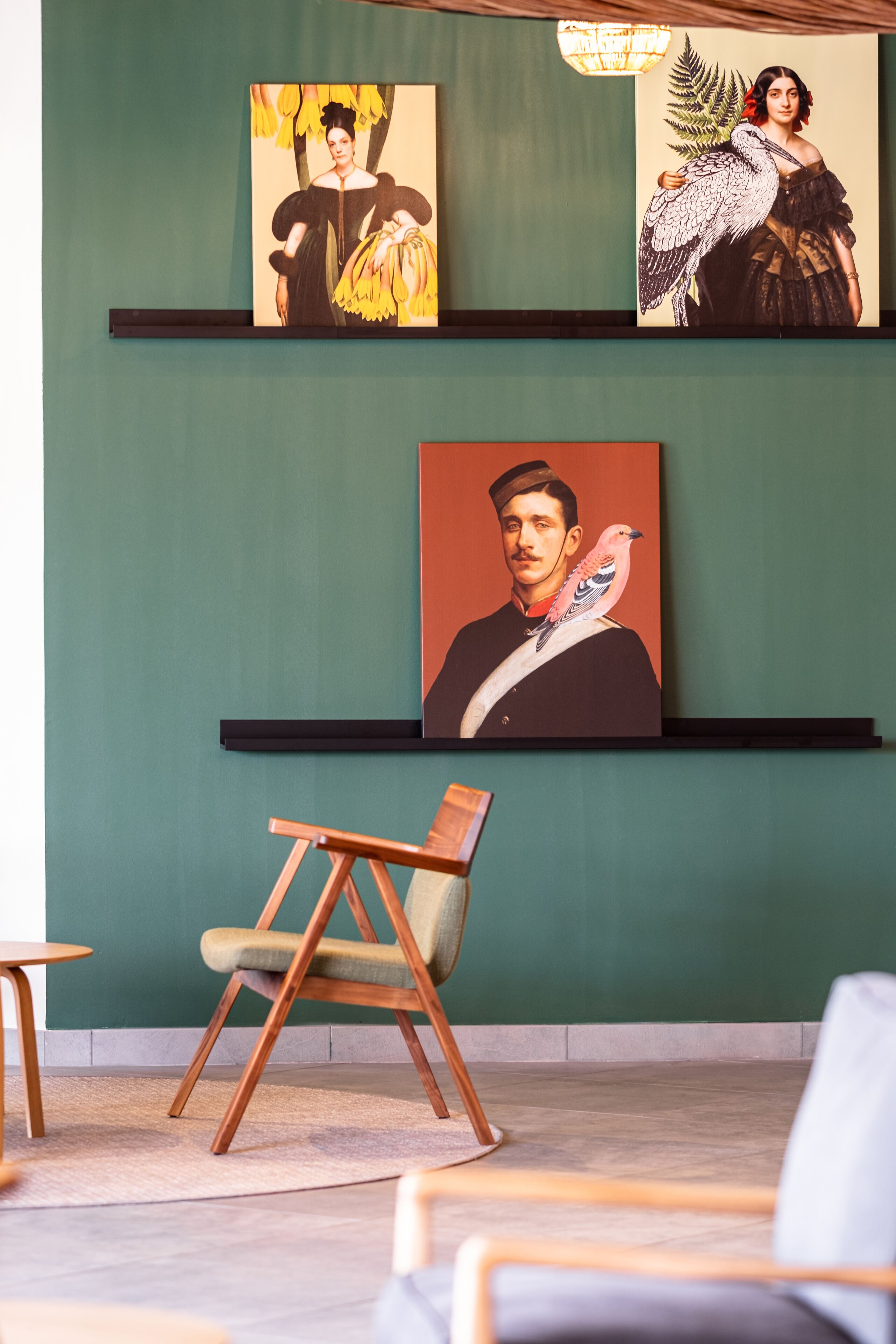 Quarto com parede verde, uma cadeira de madeira e duas obras de arte emolduradas.