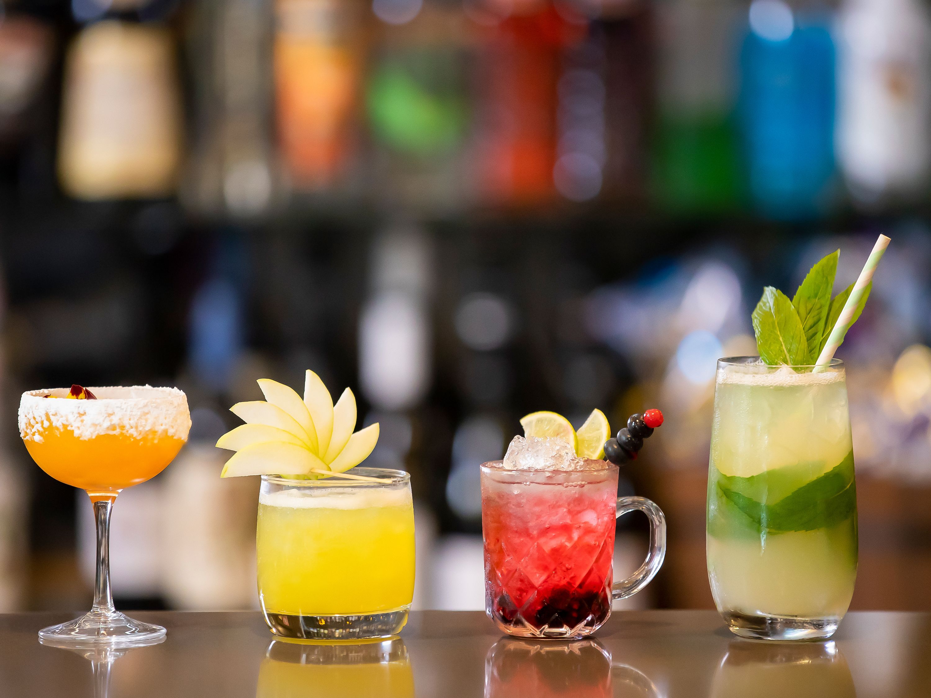 Quatro coquetéis diferentes em um balcão de bar.