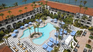 Um resort com piscina, palmeiras e piso quadriculado.